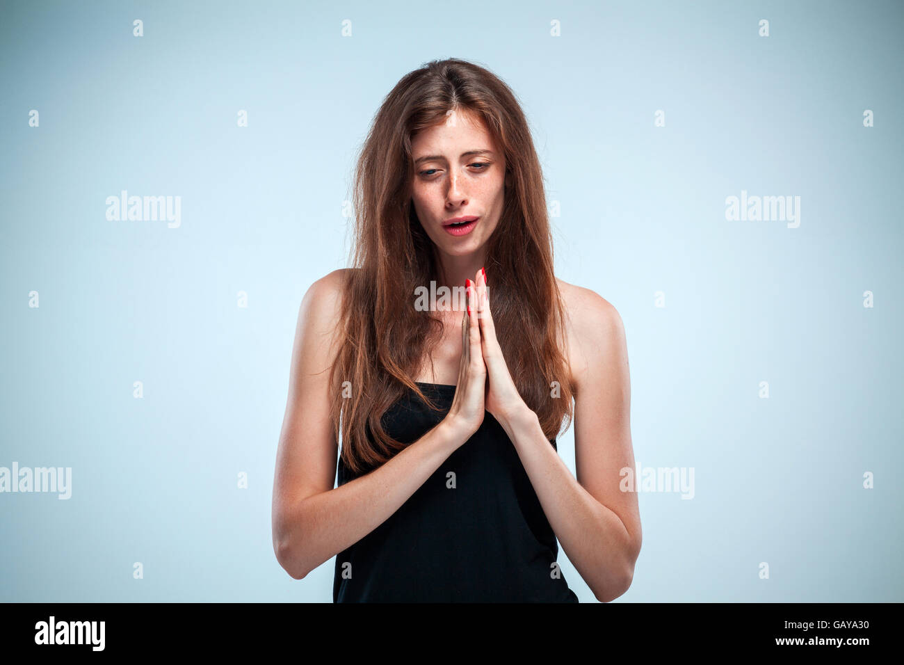 The woman is looking imploring over gray background Stock Photo - Alamy