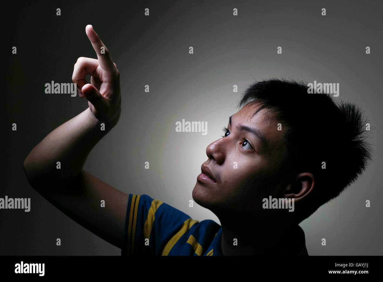 Male teenager looking up and pointing upwards Stock Photo - Alamy