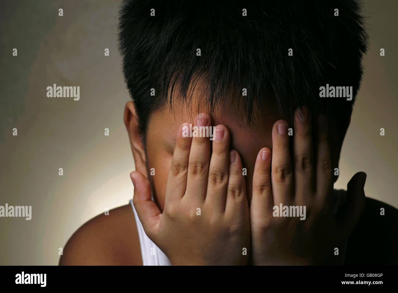 Young boy covering his face with his hand Stock Photo - Alamy