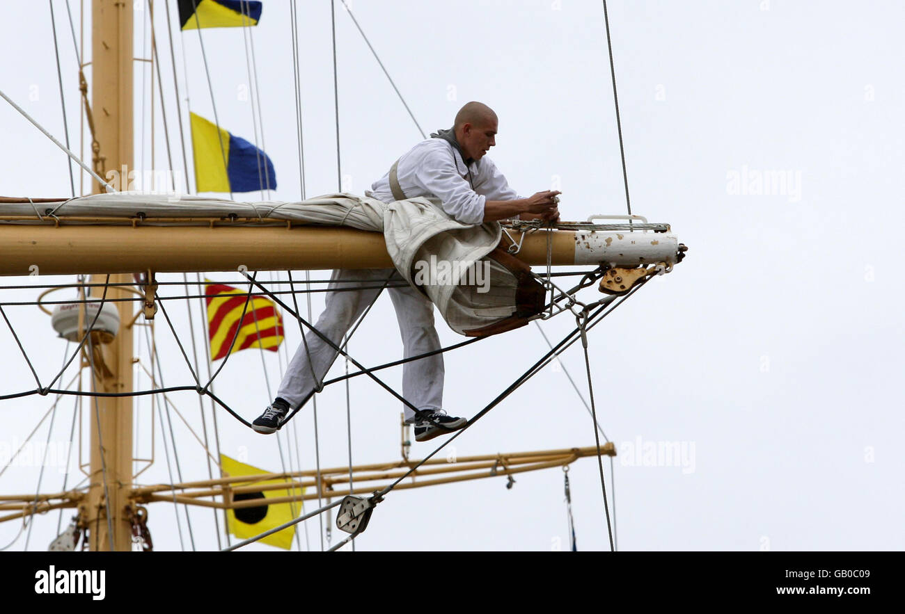 Sailors wrap up the sails on a ship moored in the Albert Dock which are ...