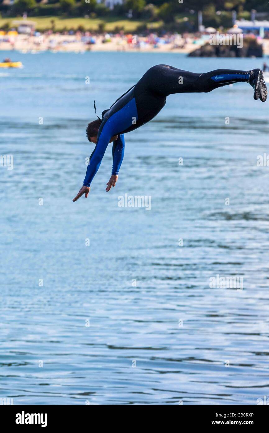 A male jumper jumping into the sea from the harbour wall at St. Ives ...