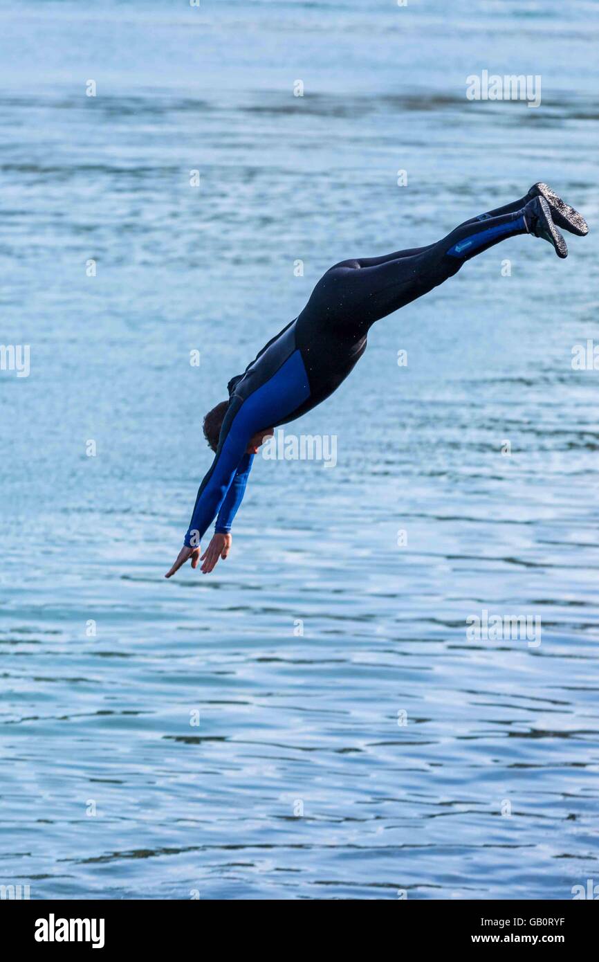 A male jumper jumping into the sea from the harbour wall at St. Ives ...