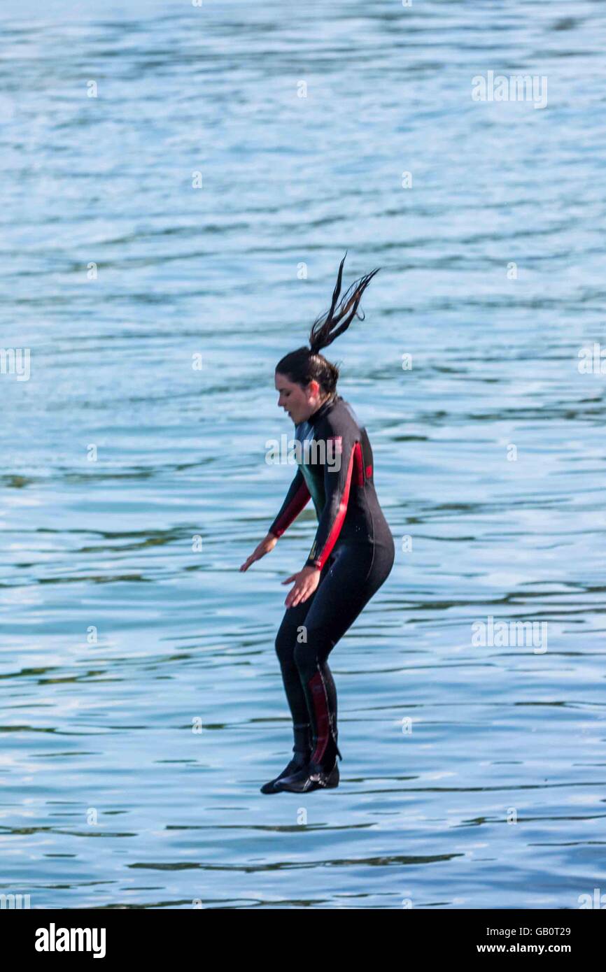 A girl jumper jumping into the sea from the harbour wall at St. Ives ...