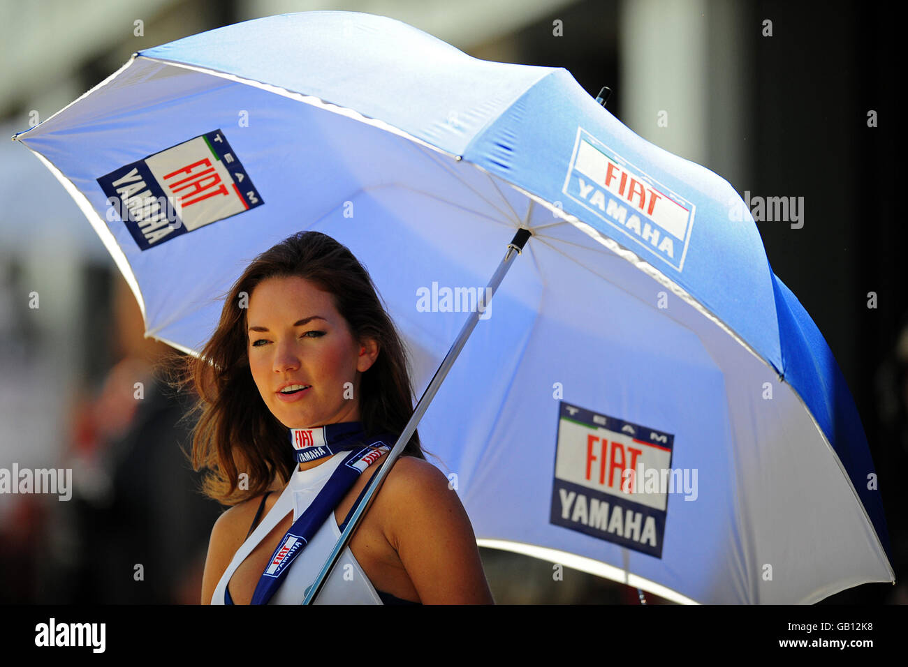 A Yamaha girl takes shade from the sun, in the pits before practice for ...