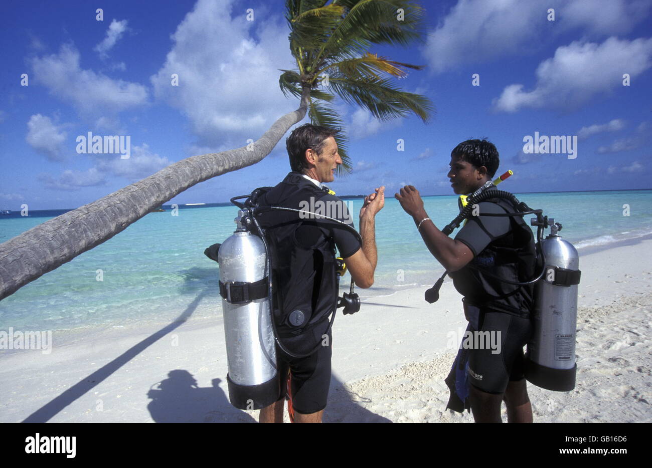 Divers on a beach with the seascape of the island and atoll of the ...