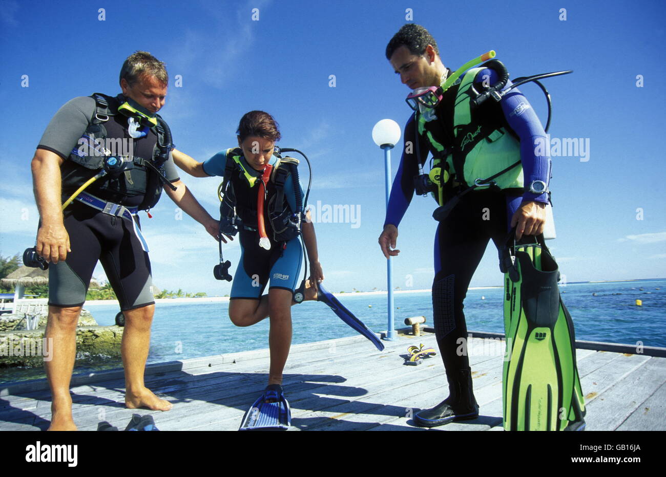 Divers on a beach with the seascape of the island and atoll of the ...
