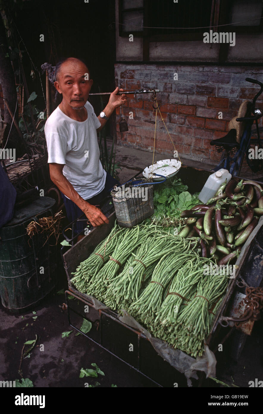 Chinese man with vegetable stall, Chengdu market, Sichuan Province ...