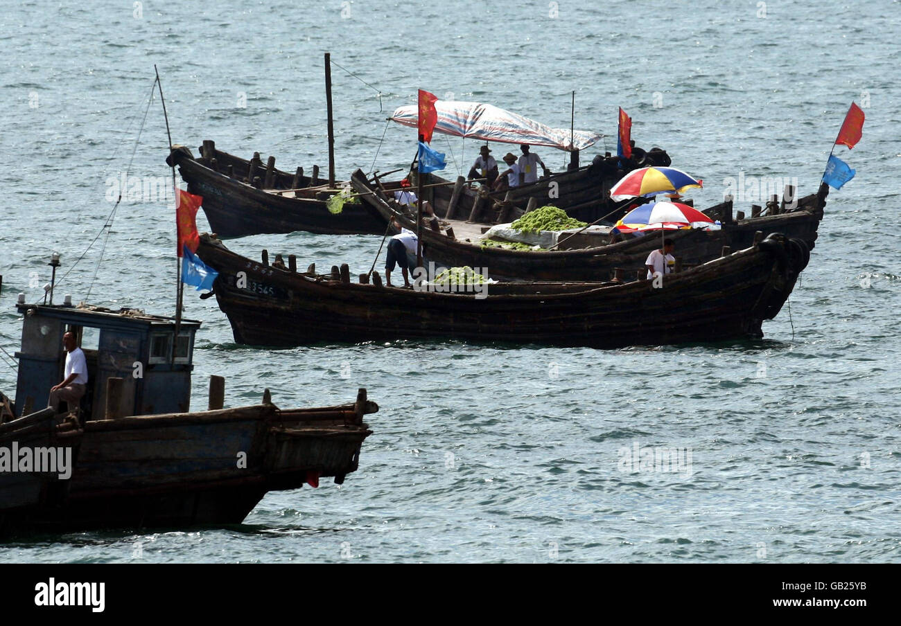 Local boats collect seaweed from the Olympic sailing course off Qingdao ...