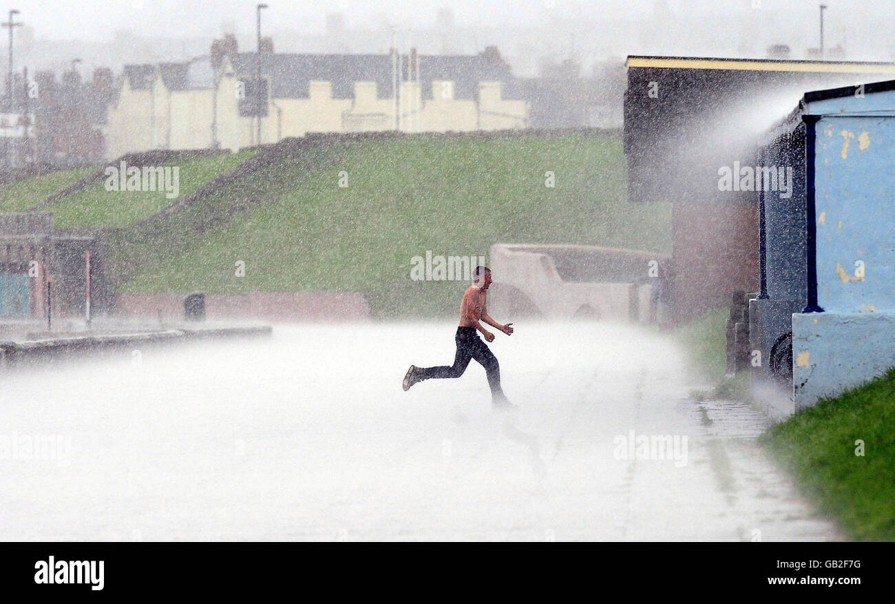 A man runs for cover after being caught in a sudden rain storm on the ...