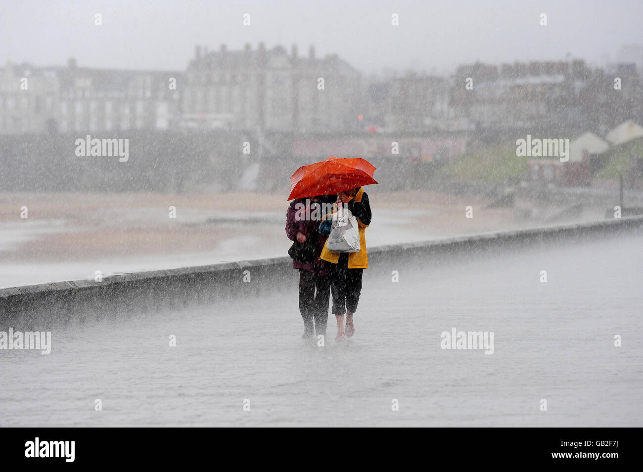 Two people are caught up in a sudden rain storm on Whitley Bay beach ...