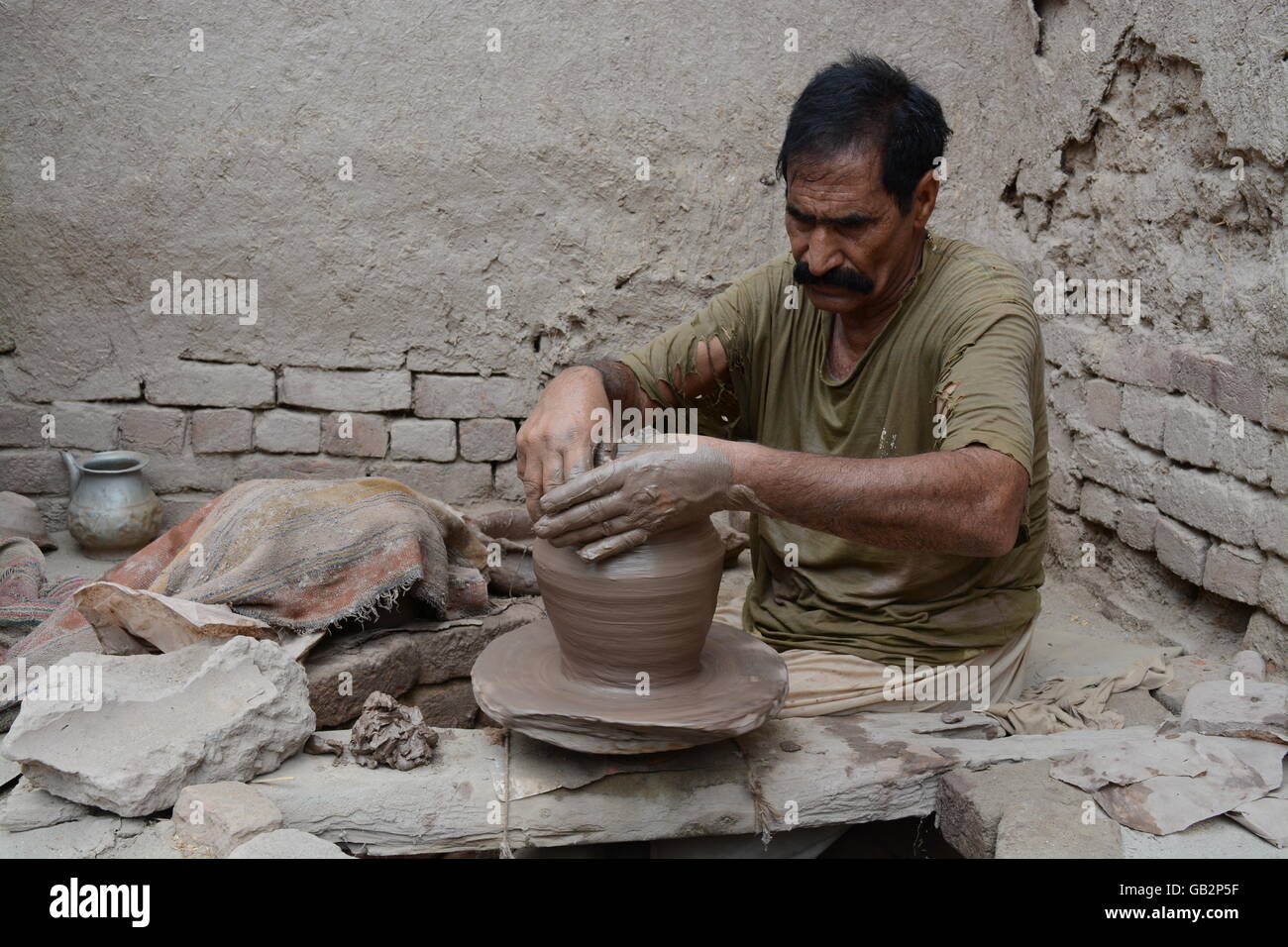 Potter is busy in making pottery on wheel and his body is sweating by ...
