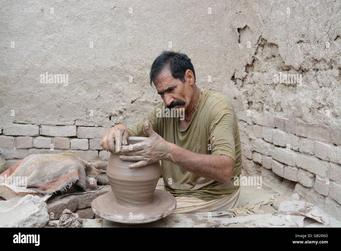 Potter is busy in making pottery on wheel and his body is sweating by ...