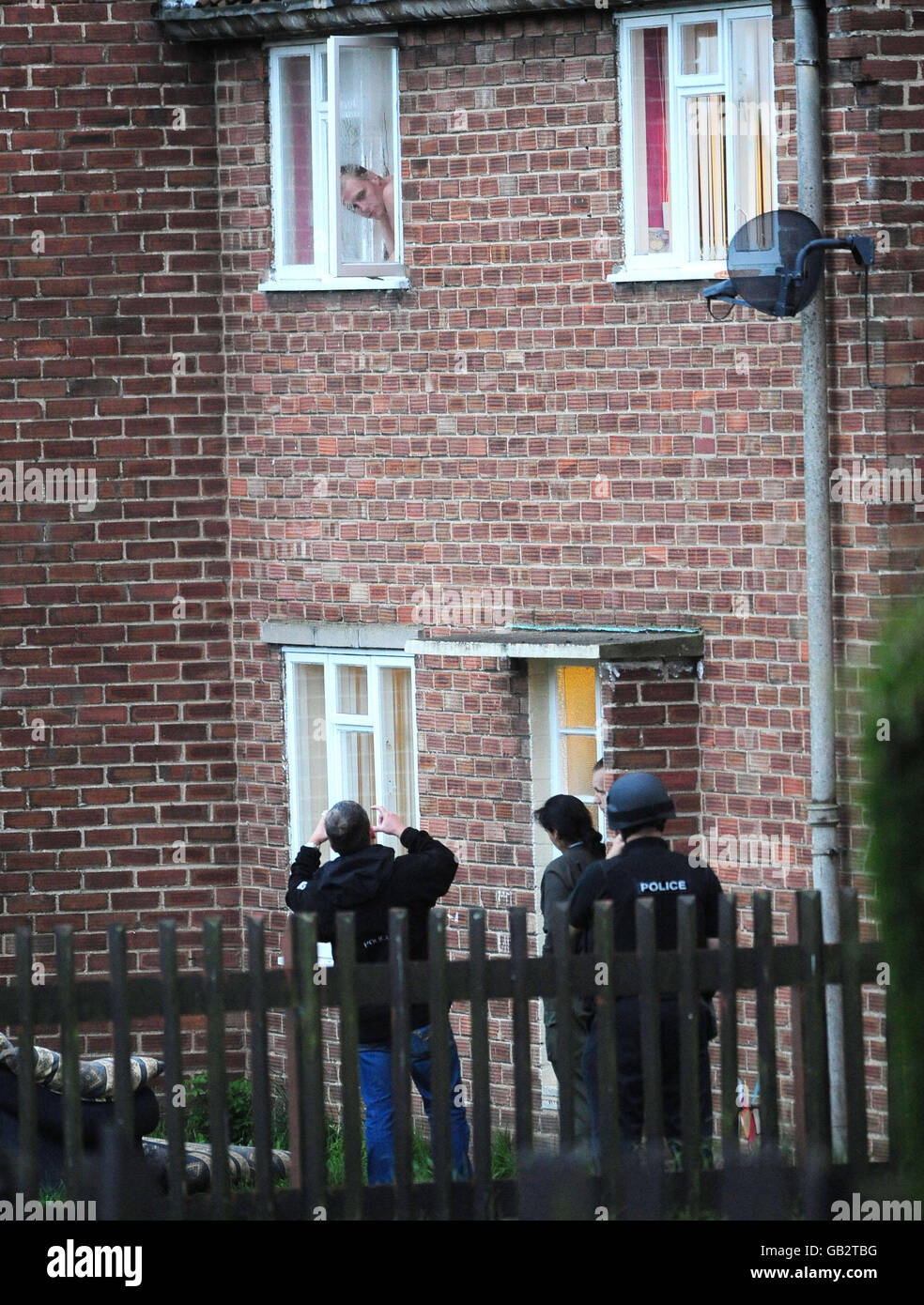 A man talks to police officers from an upstairs window in the house in ...