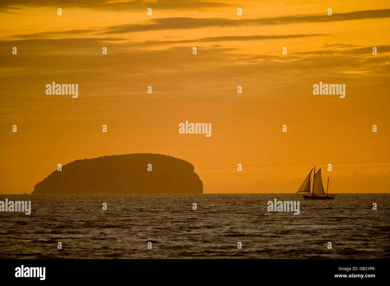 The sun casts a golden glow as it sets over Steep Holme Island situated ...