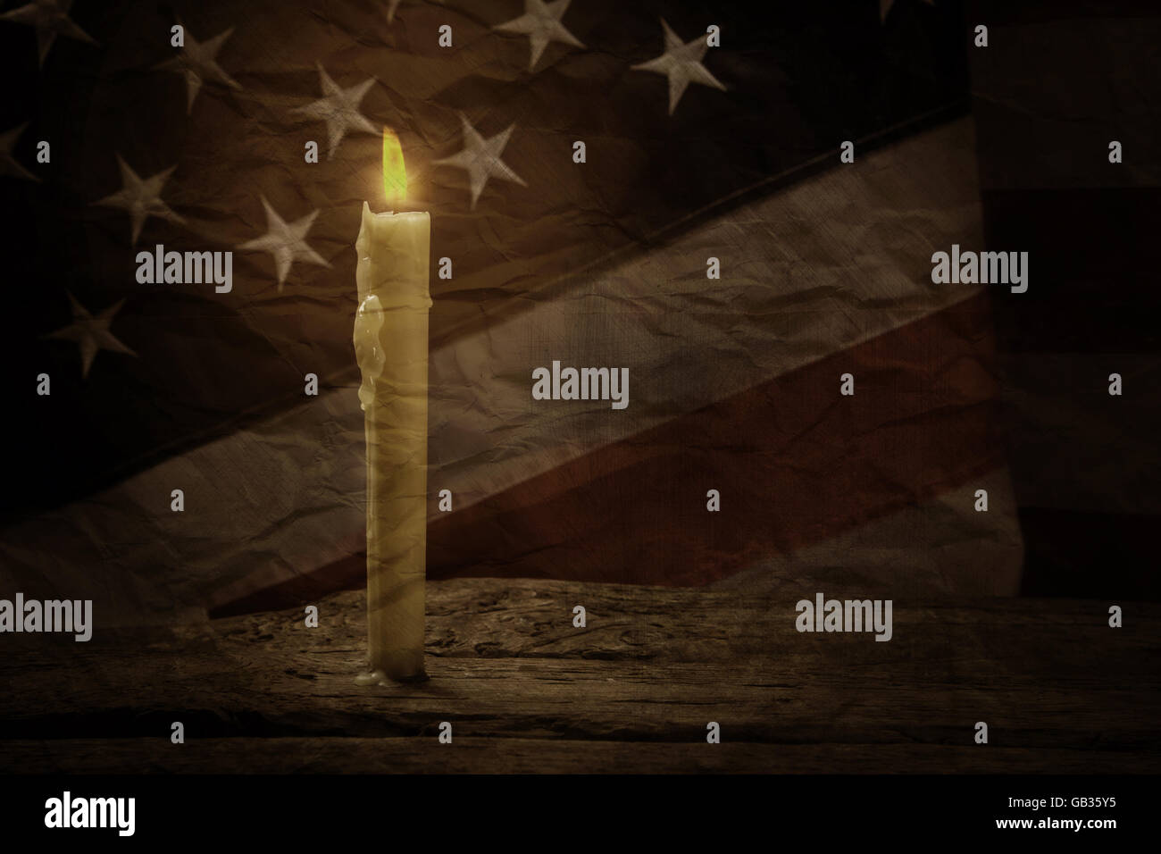 Old american flag behind candle. Burning candle in the darkness ...