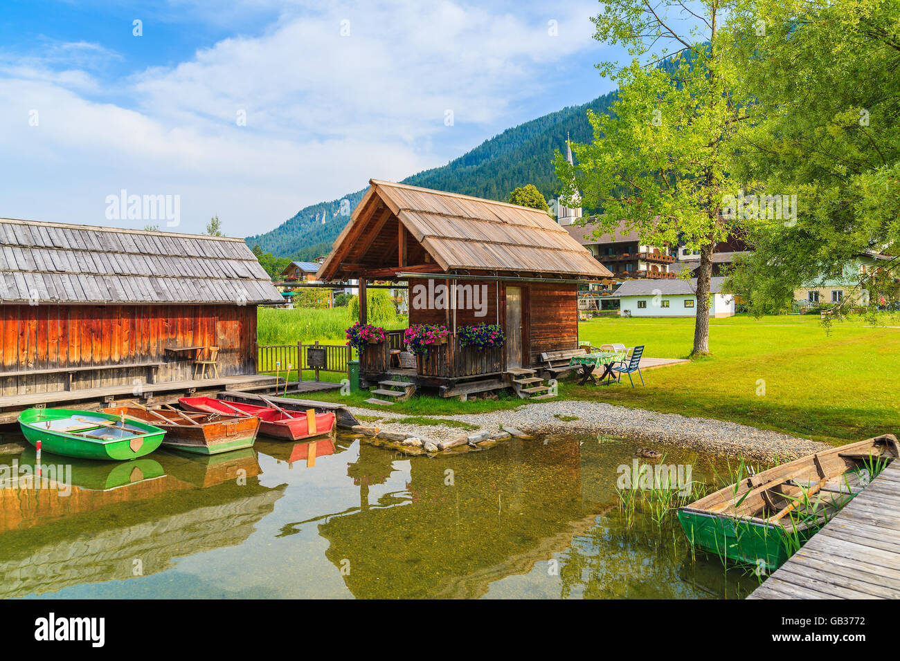 Fishing boats and wooden cabins on shore of Weissensee lake in summer ...