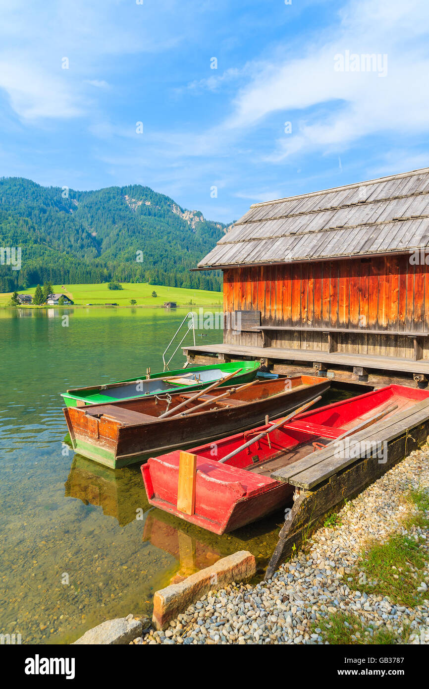 Two colorful fishing boats and wooden cabin on shore of Weissensee lake ...