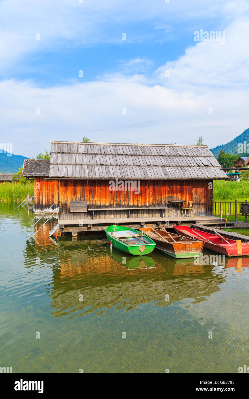 Three colorful fishing boats and wooden cabin on shore of Weissensee ...