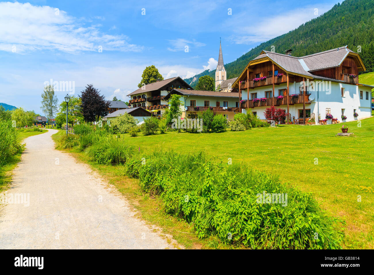 Walking path in small alpine village on shore of Weissensee lake with ...