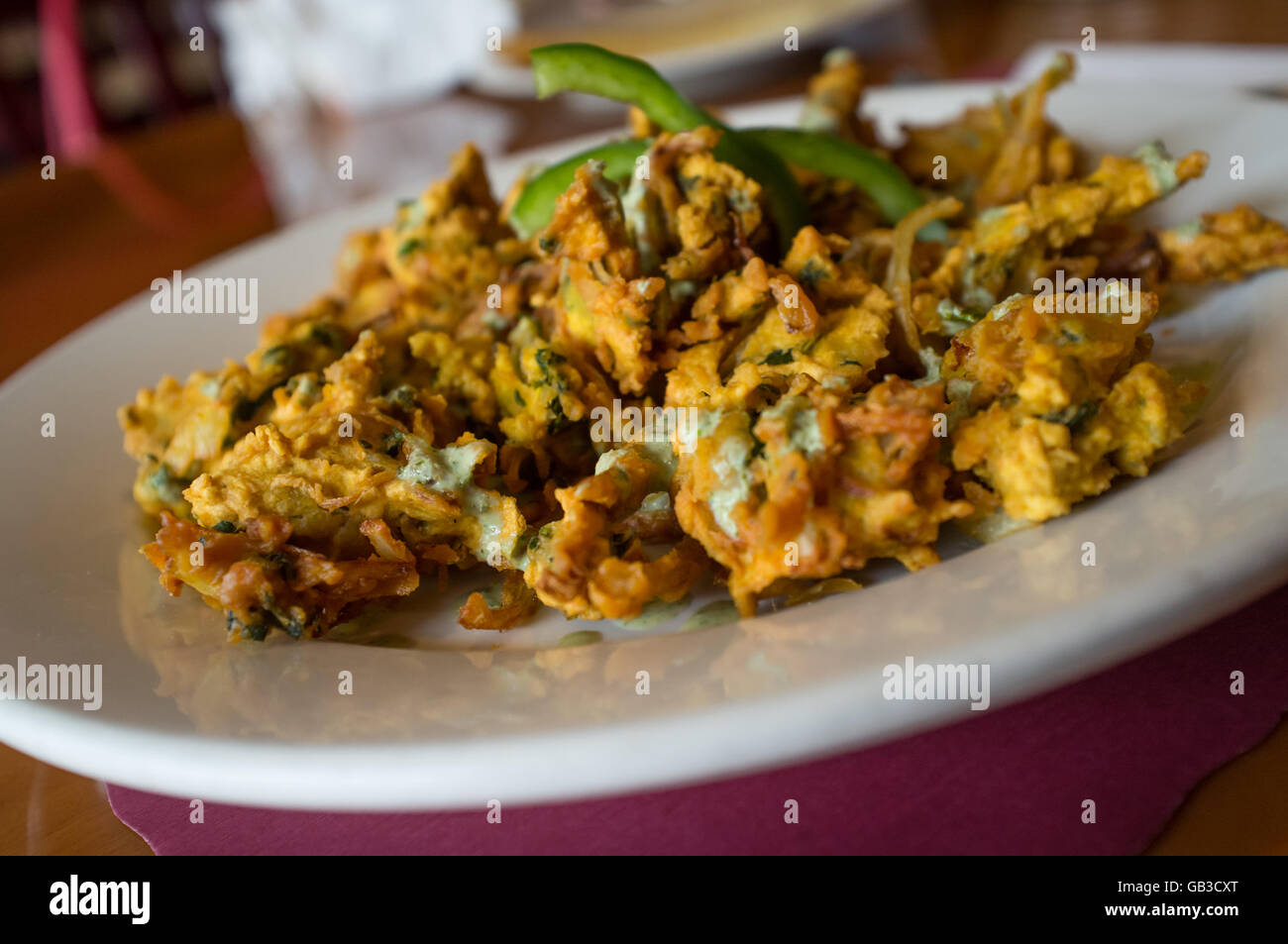 Deep fried breaded Indian onion pakora with green bell pepper garnish ...