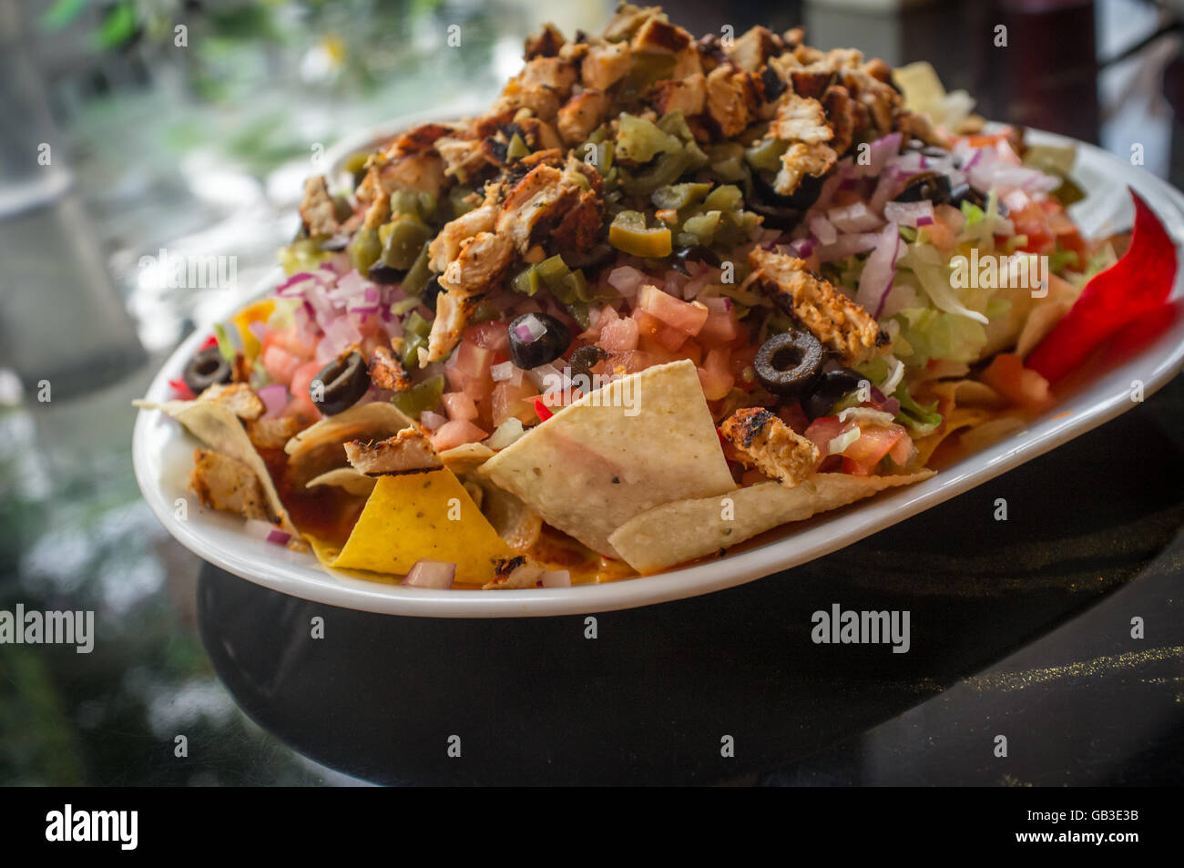 Colorful Mexican nachos with chicken black olives melted cheese ...