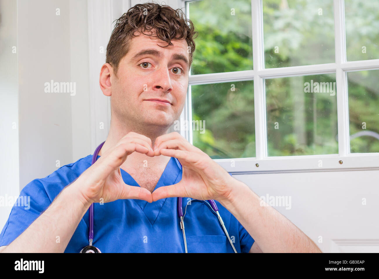 Male nurse in scrubs with stethoscope heart hand sign Stock Photo - Alamy
