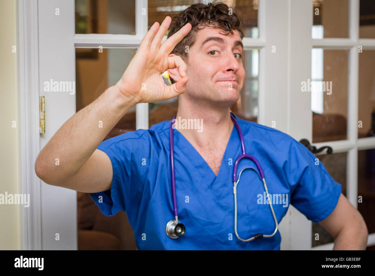 Male nurse in scrubs with stethoscope making okay hand sign Stock Photo ...