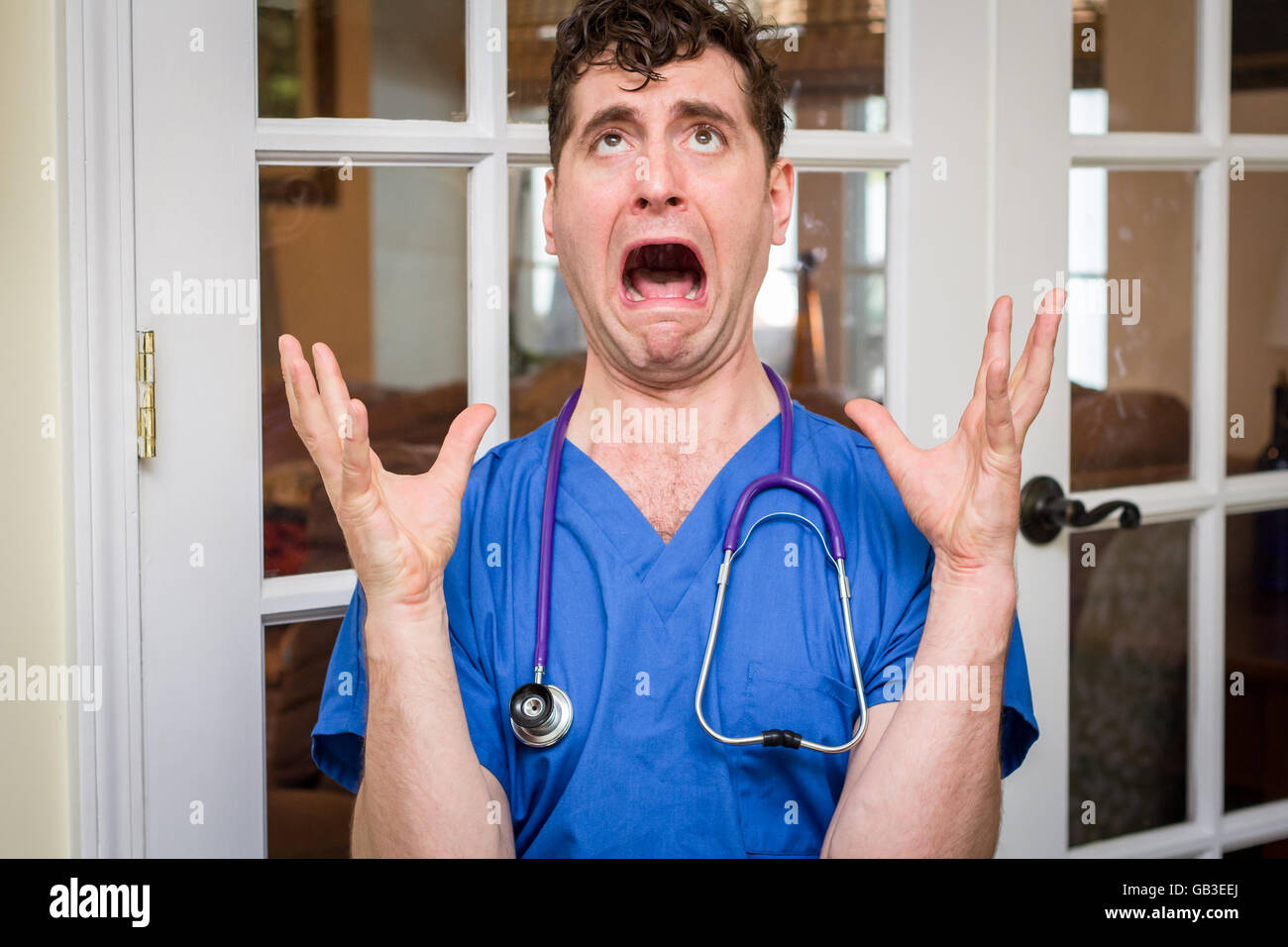 Male nurse in scrubs with stethoscope overwhelmed and panic stricken ...