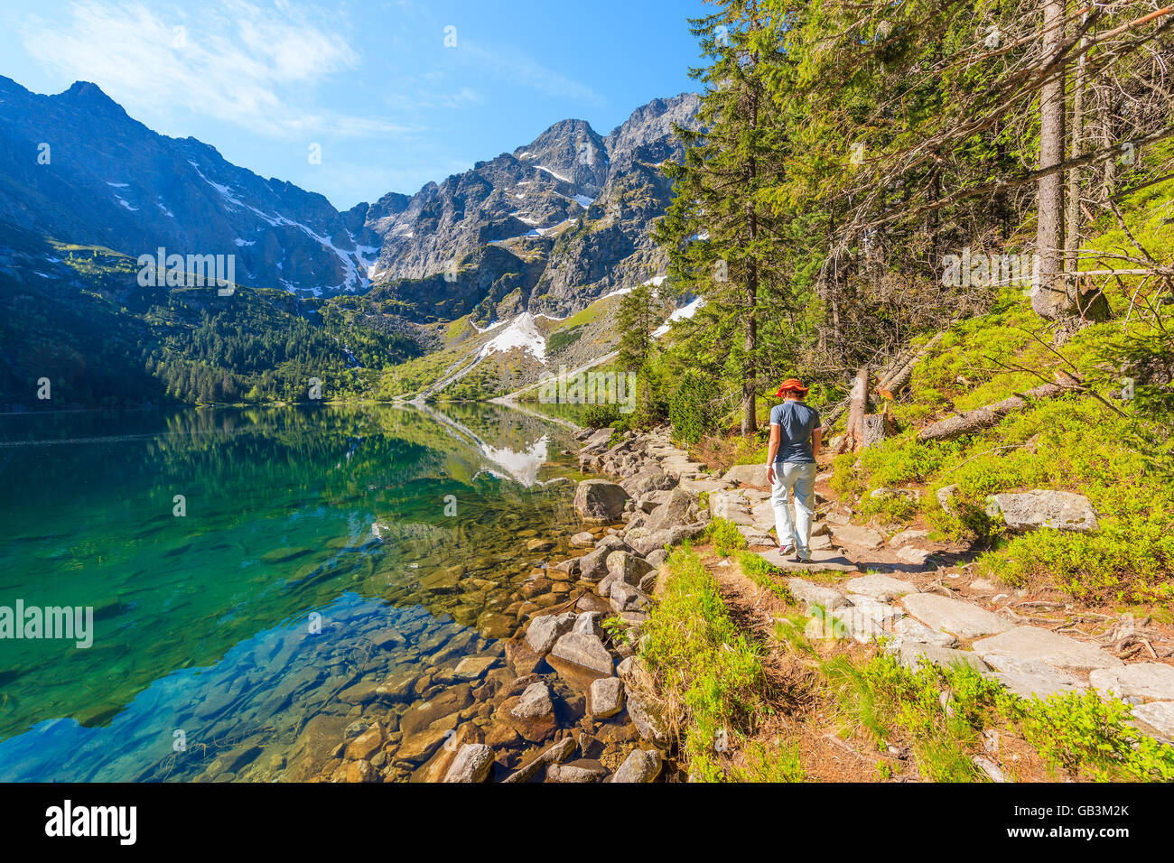 Young woman tourist walking on path along beautiful green water Morskie ...