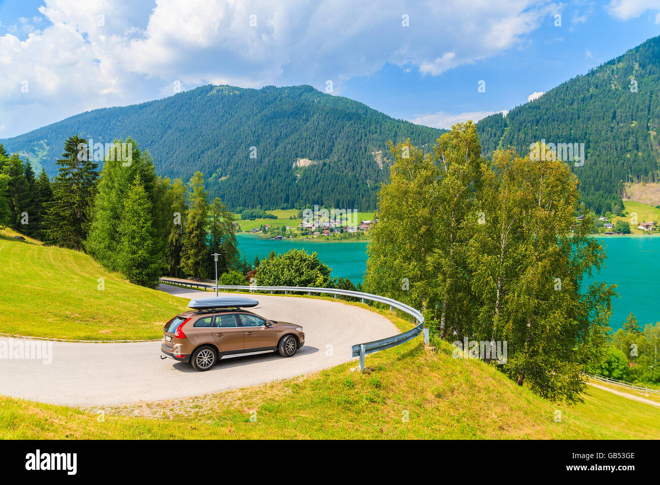 Car on scenic mountain road driving along Weissensee lake in summer ...