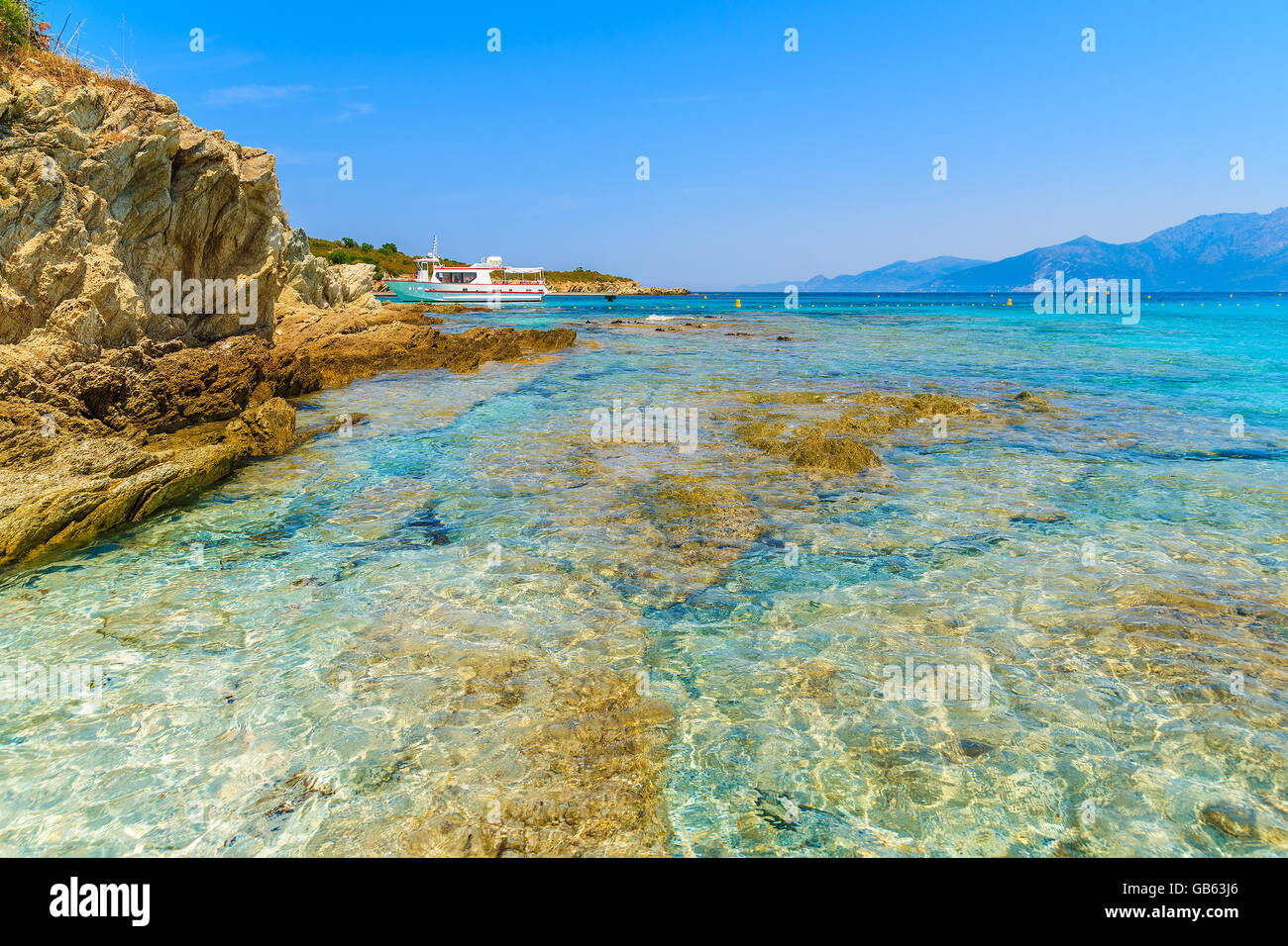 Crystal clear sea water of Lotu beach with tourist boat in distance ...