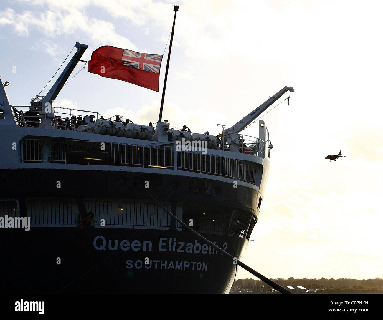 A sea harrier flies past the QE2, with the vessel's flag at half mast ...