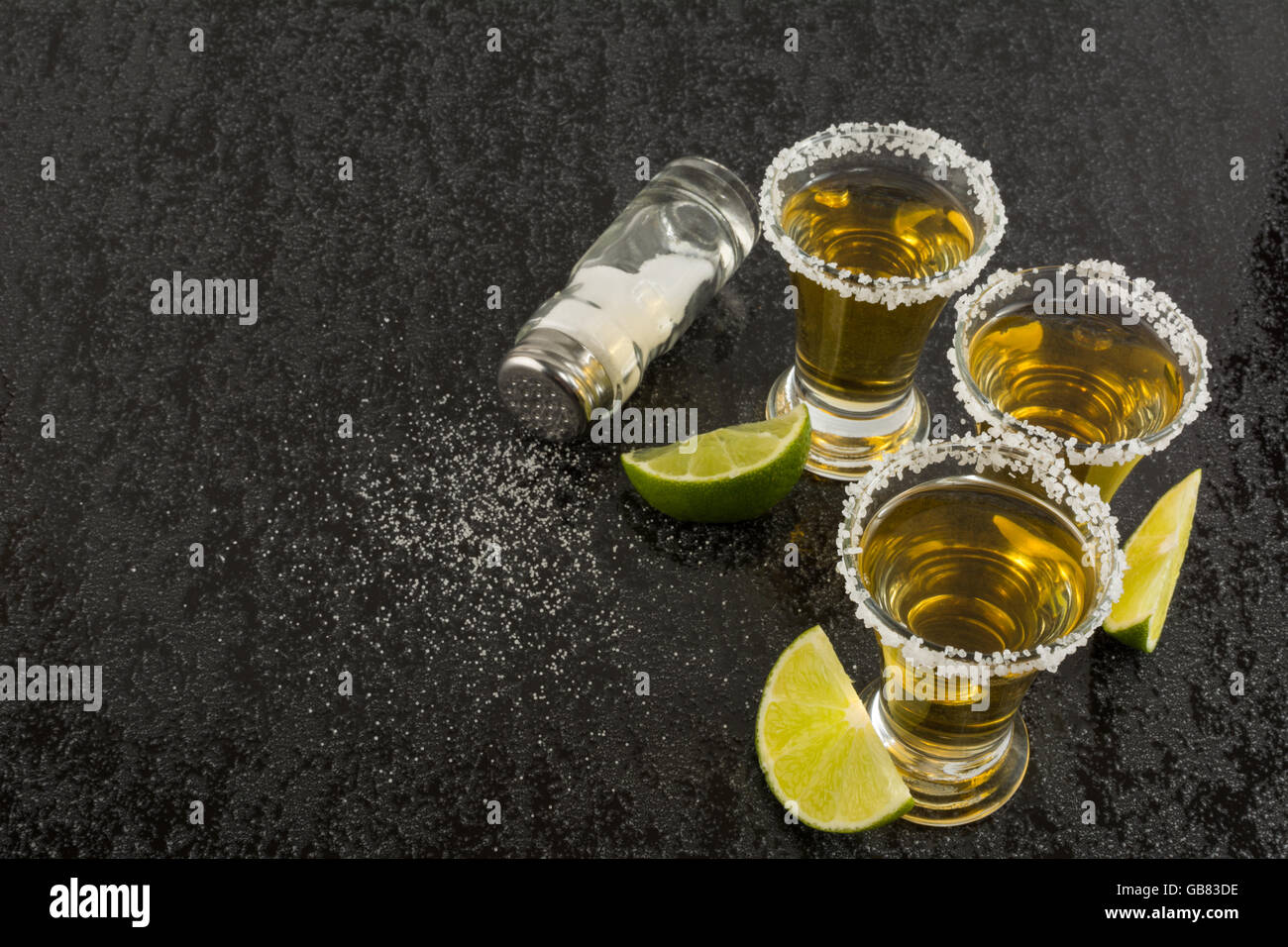 Tequila shots with lime and salt on black table. Tequila. Gold Mexican ...