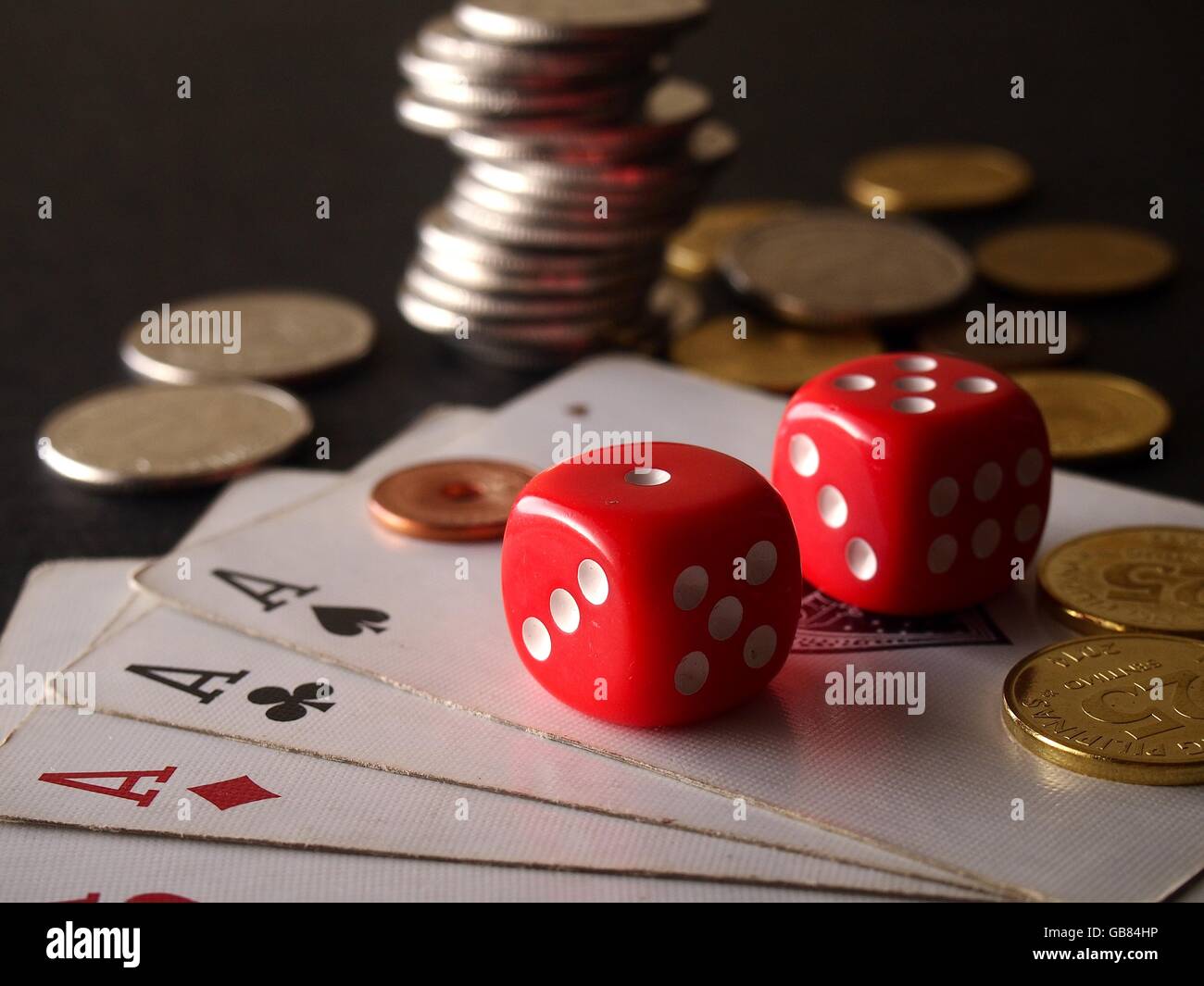 Two red dice, game cards and stack of coins Stock Photo - Alamy