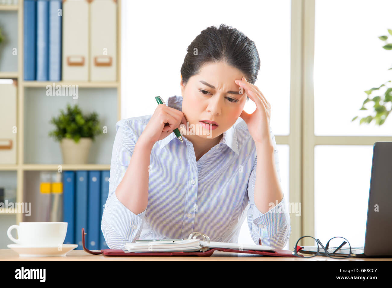 Young asian business woman writing with headache in office Stock Photo ...