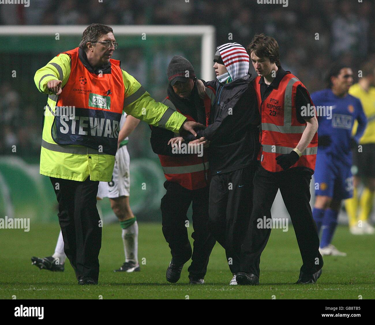 A Pitch Invader (2nd right) is escoted from the field of play after ...