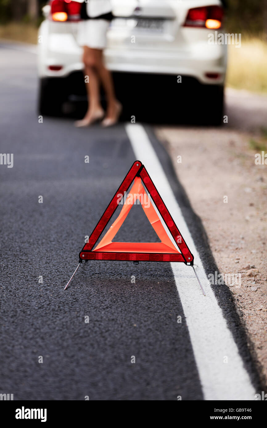 Red warning triangle and broken car in the middle of forrest Stock ...