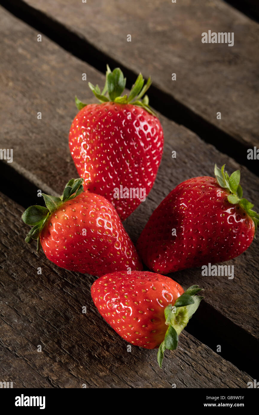 Four juicy strawberry on wooden plank Stock Photo - Alamy
