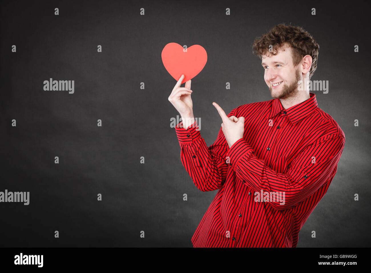 Love and help from people. Charming lovely man with red paper heart ...