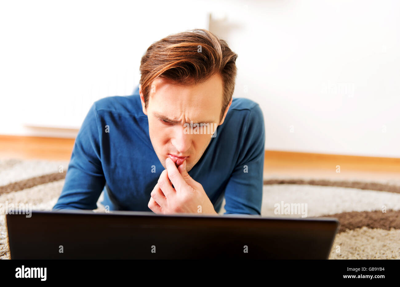 Young man lying on the floor and using laptop Stock Photo - Alamy