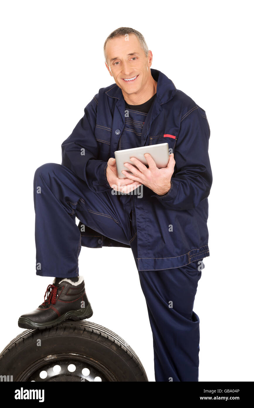 Smiling mechanic with a tire and tablet Stock Photo - Alamy