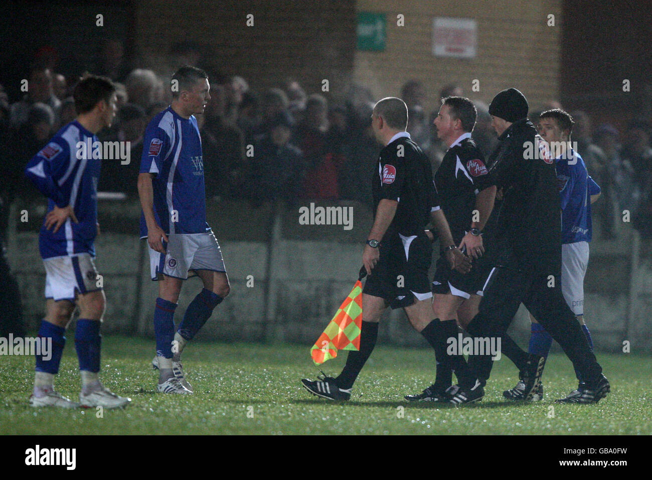 Assistant referee Paul Curry (centre, holding flag) is lead away by ...