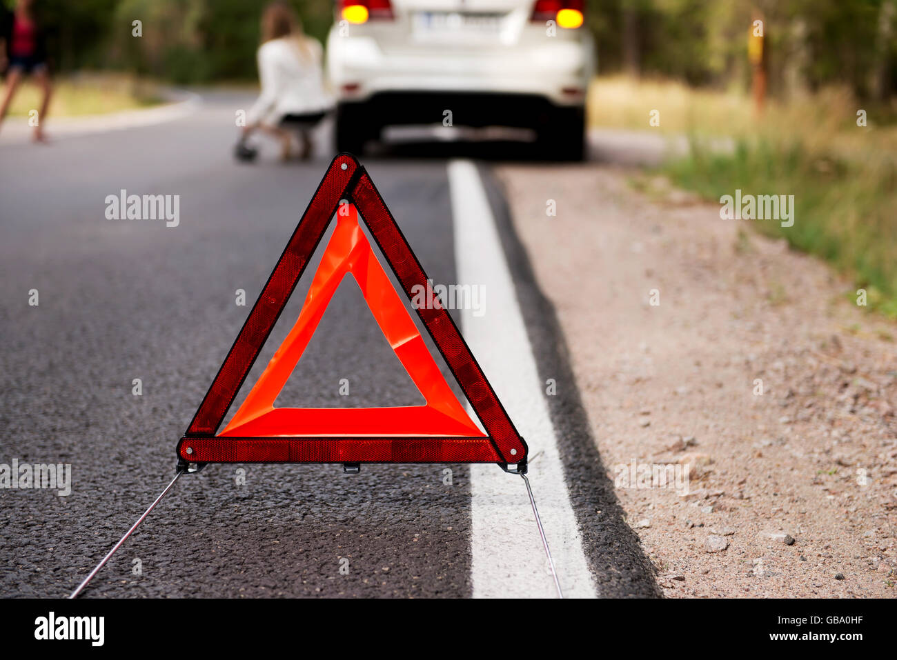 Red warning triangle and broken car in the middle of forrest Stock ...