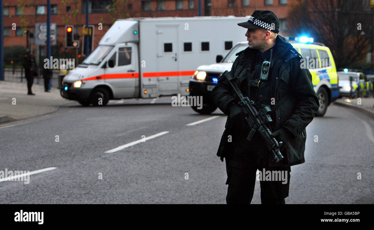 A policeman stands guard as an escorted security van arrives outside ...