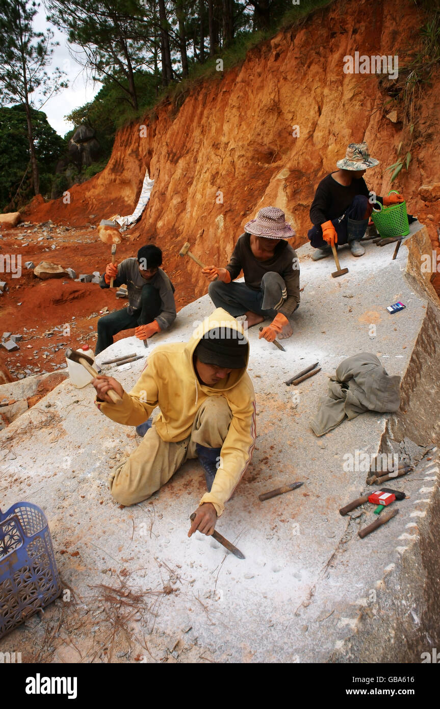 Two Workers with splitter on hand try to split large rock into small ...