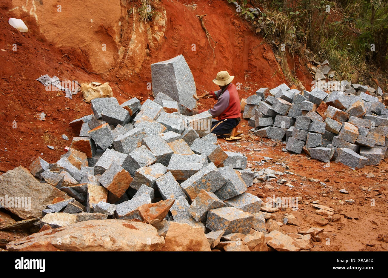 Two Workers with splitter on hand try to split large rock into small ...