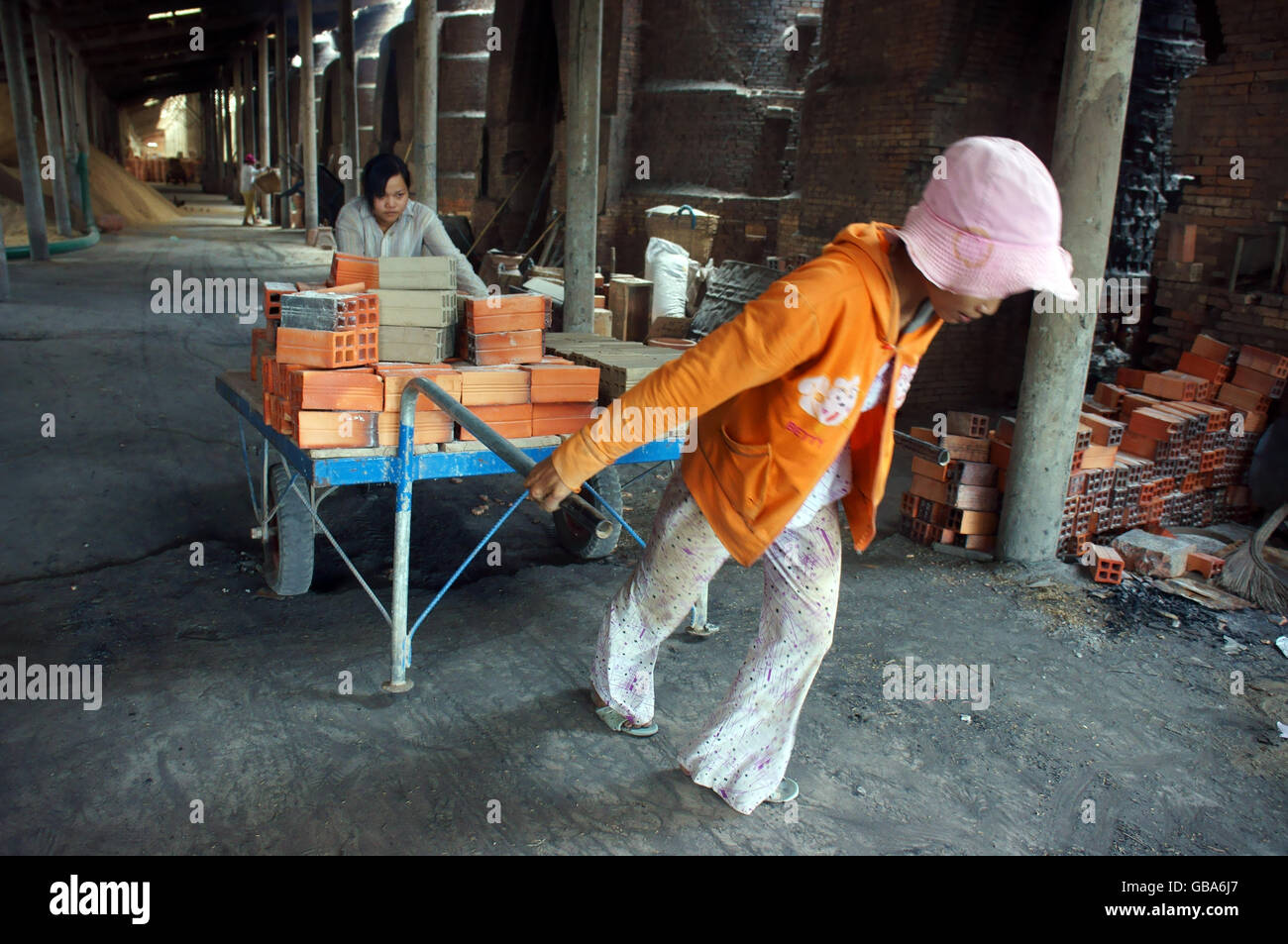 Worker working at brick factory, workwoman in hard work, pulling up the ...