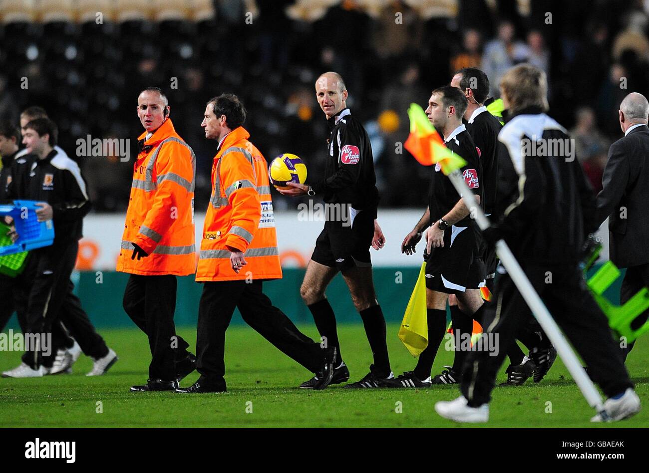 Referee Mike Riley (centre) makes his way off the field surrounded by ...