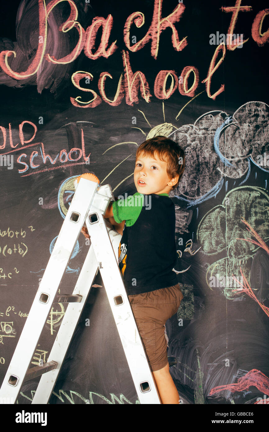 little cute real boy at blackboard in classroom, back to school close ...