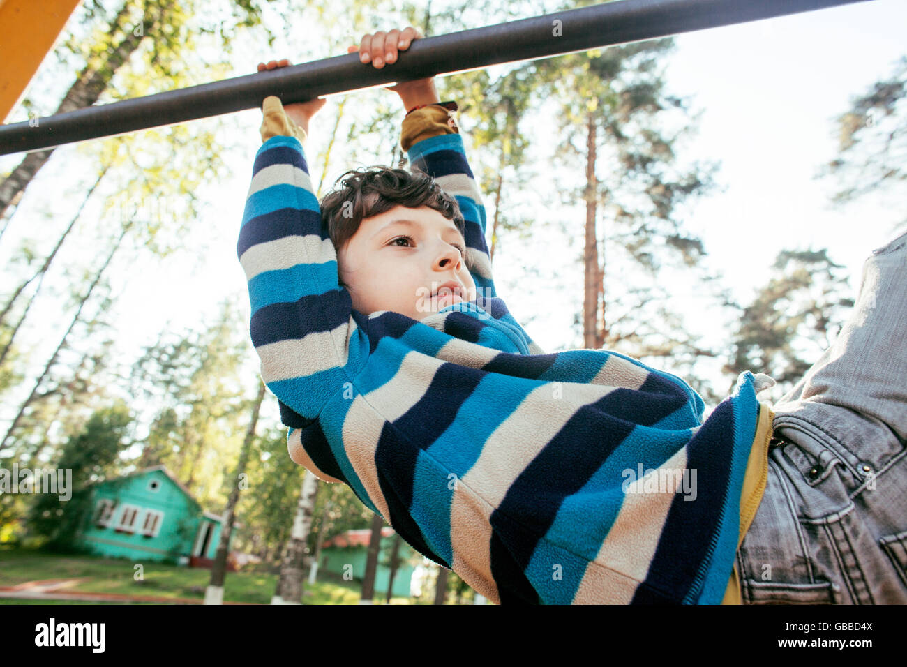 little cute blond boy hanging on playground outside, alone training ...